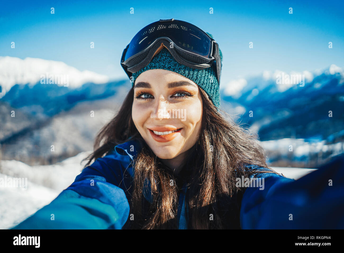 Attractive snowboard girl smiling and making selfie on mountain ...