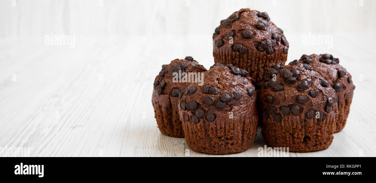 Chocolate cupcakes on white wooden table, side view. Space for text ...
