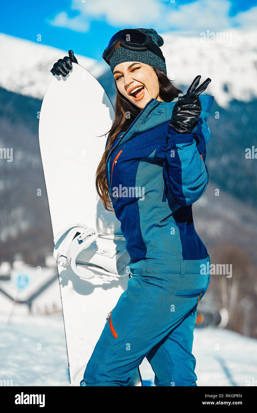 Attractive snowboard girl smiling and posing on mountain and slope ...