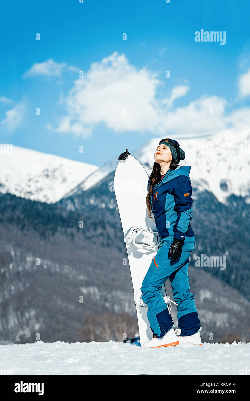 Attractive snowboard girl smiling and posing on mountain and slope ...