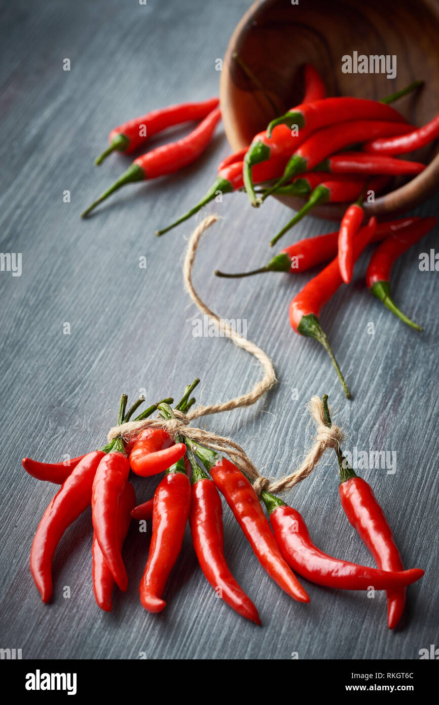 Closeup on red hot chili peppers tied with a string over dark wooden ...