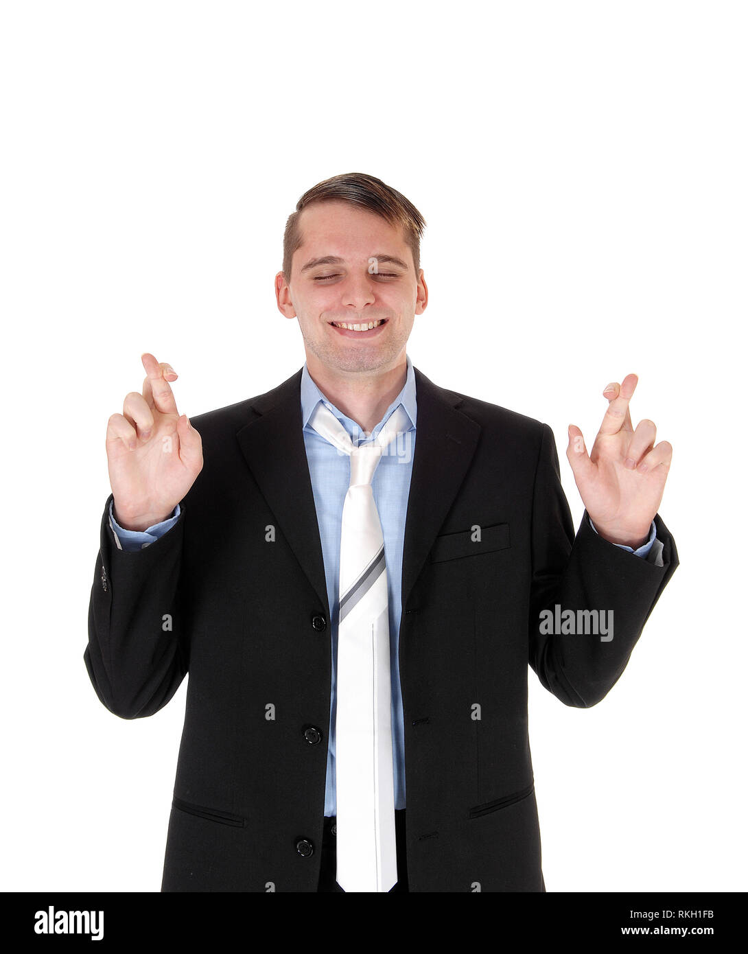 A young business man standing in a suit and tie with his fingers ...