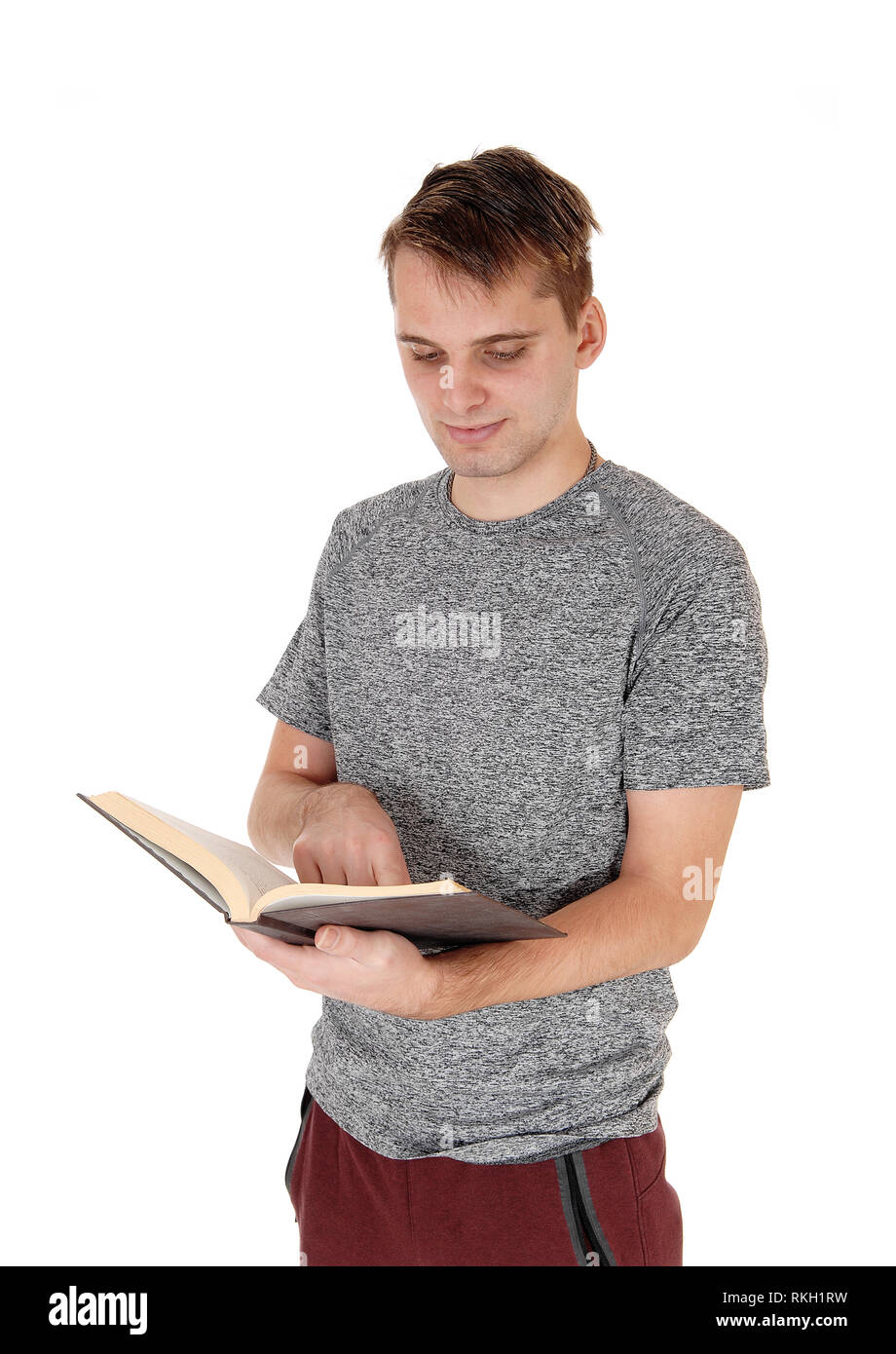A halve length body image of a young man standing and reading his book ...