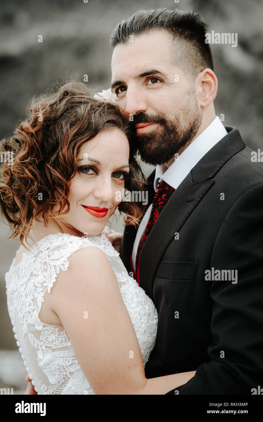 The bride and groom leaned against each other. They look at the camera ...