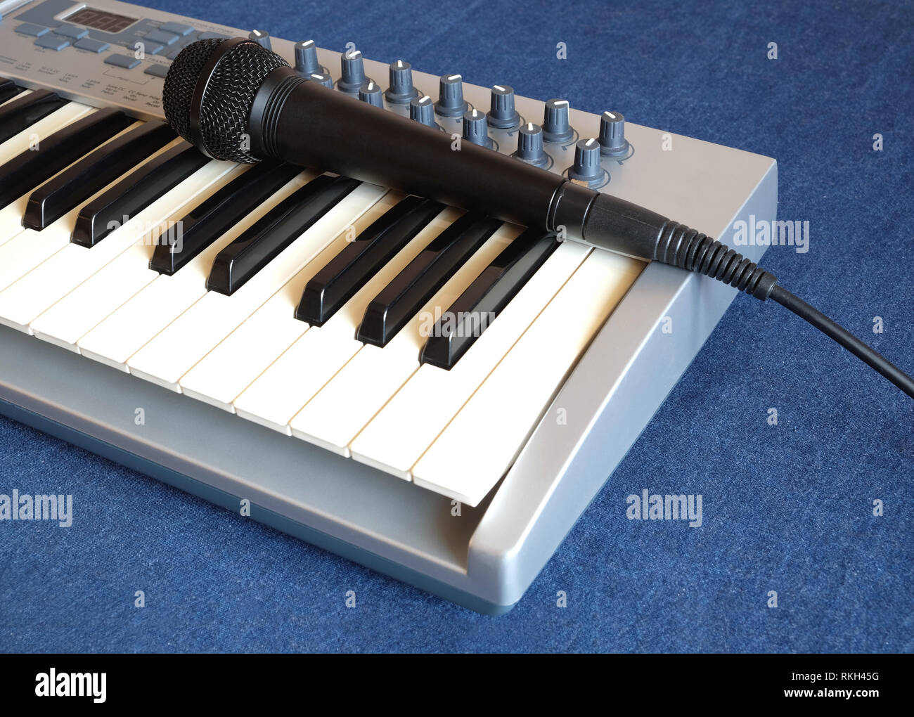 Black microphone on electronic synthesizer keyboard with many control ...