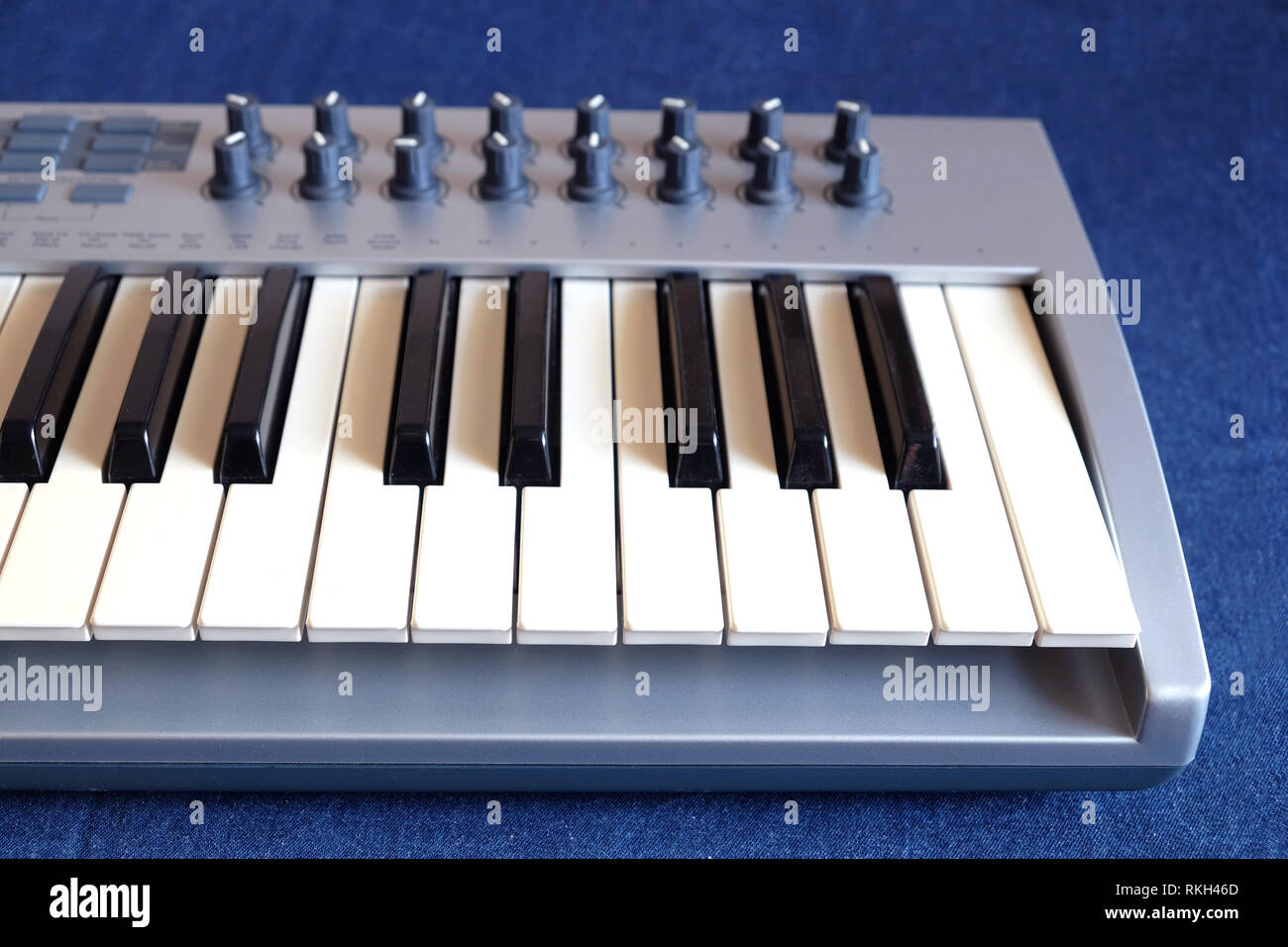 Electronic synthesizer keyboard with many control knobs on denim ...