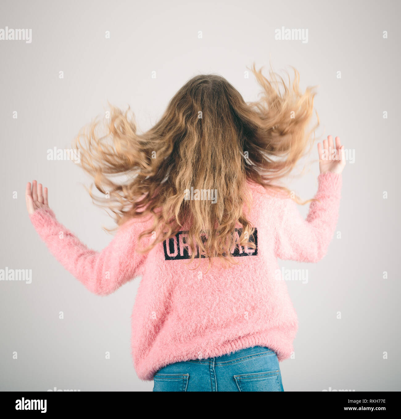 Back view of girl jumping in the air over plain background Stock Photo ...