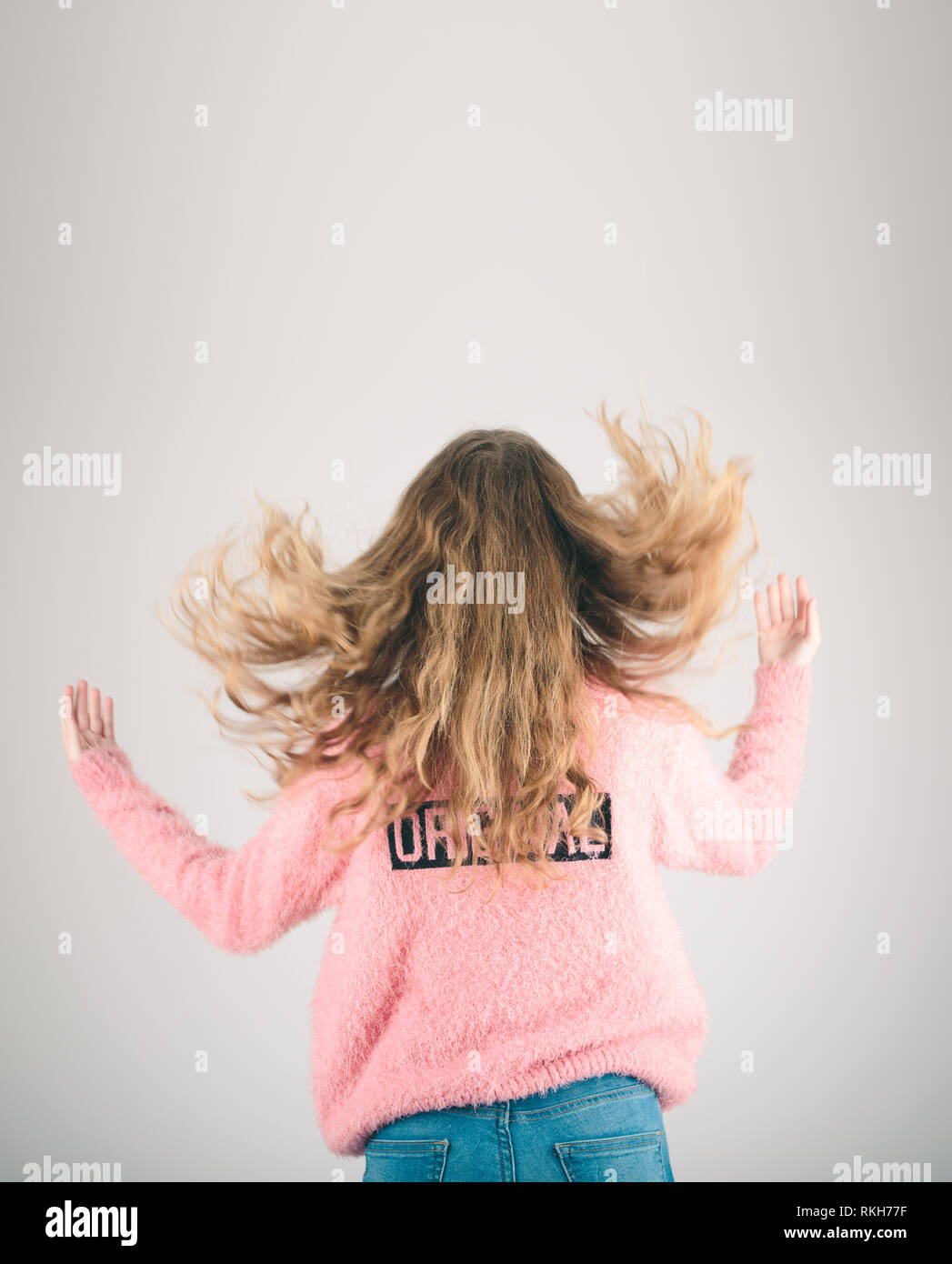 Back view of girl jumping in the air over plain background Stock Photo ...