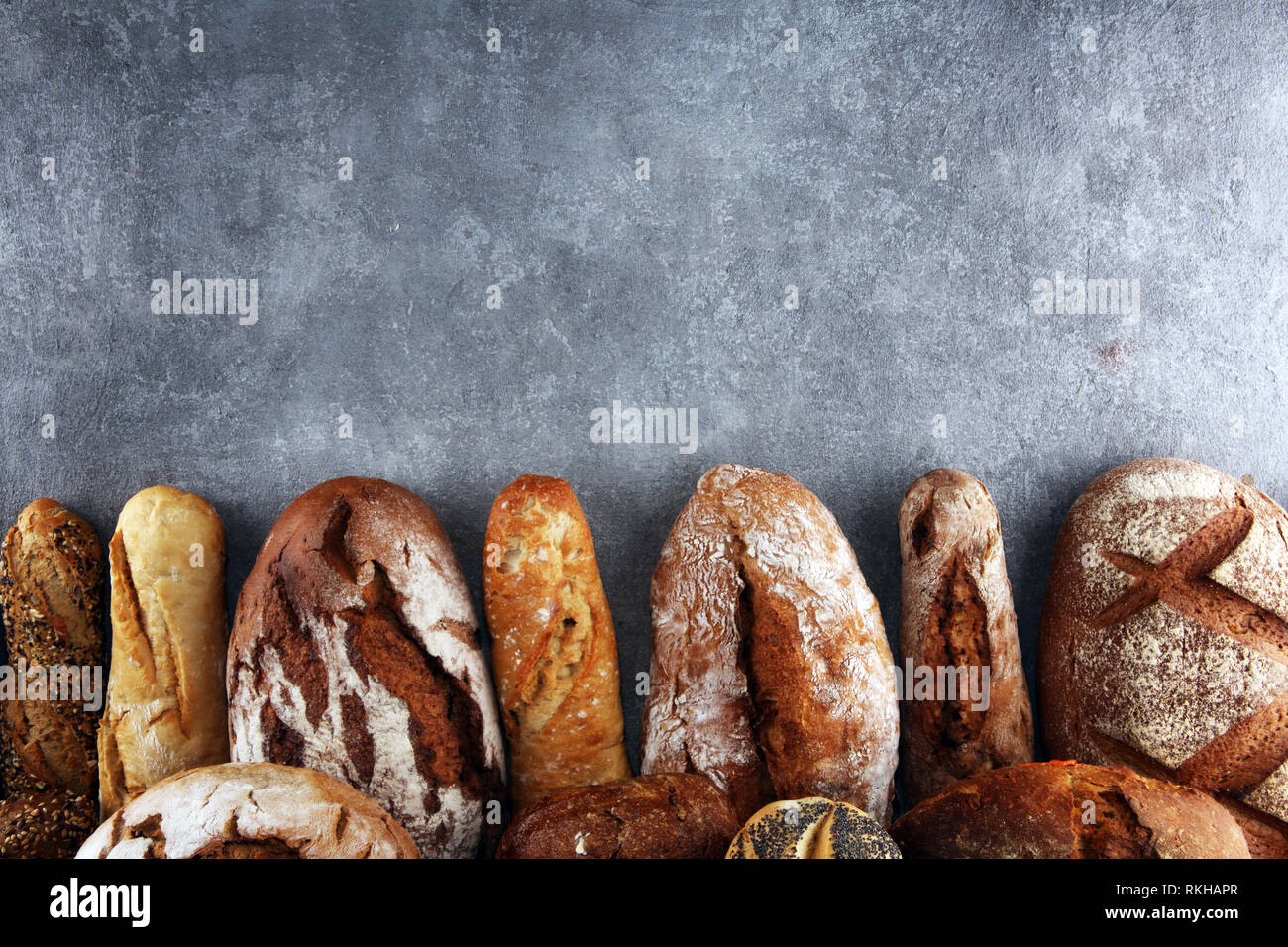 Assortment of baked bread and bread rolls on stone table background ...