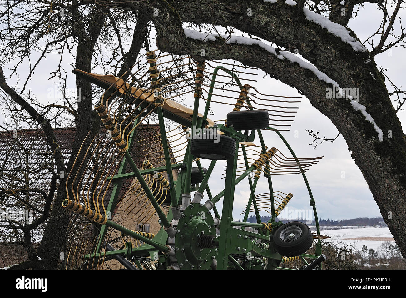 part of a large hay tedder with yellow tines on a farmyard in winter ...
