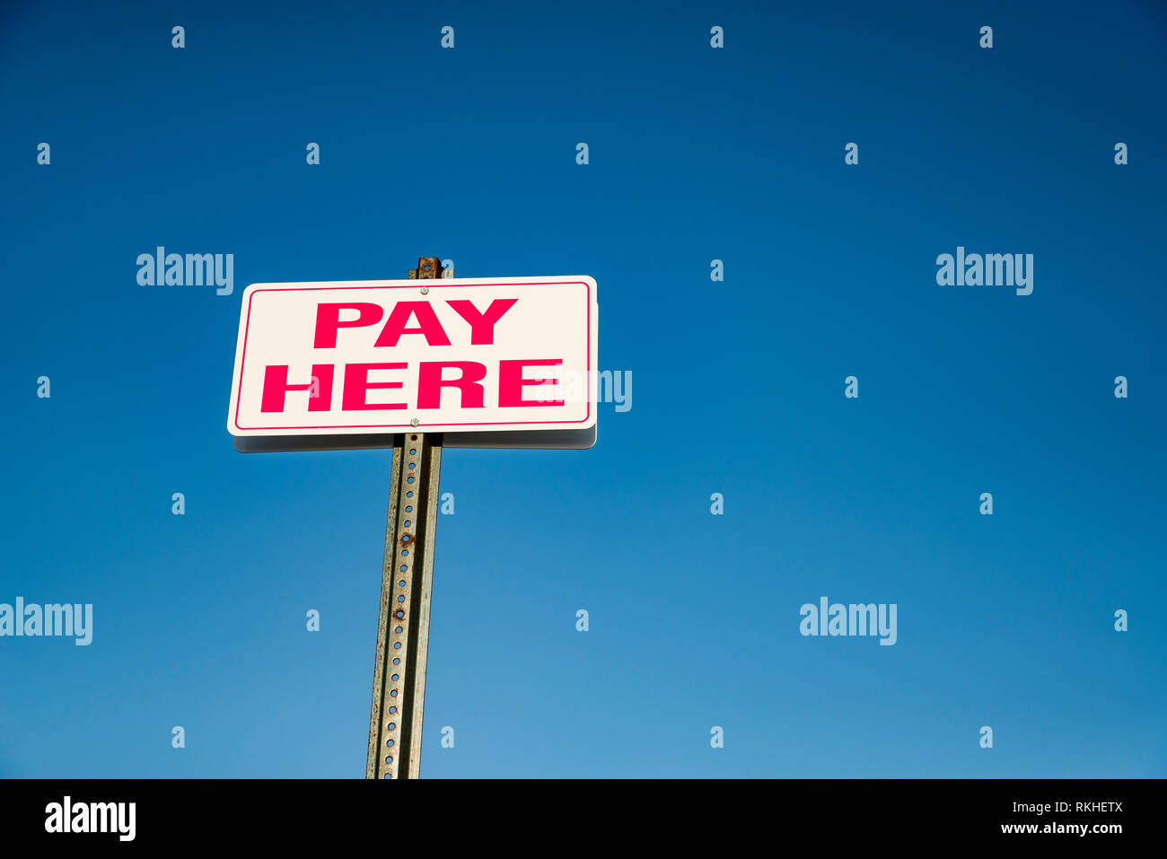 Pay Here signboard on top of an exterior wall with parked cars Stock ...