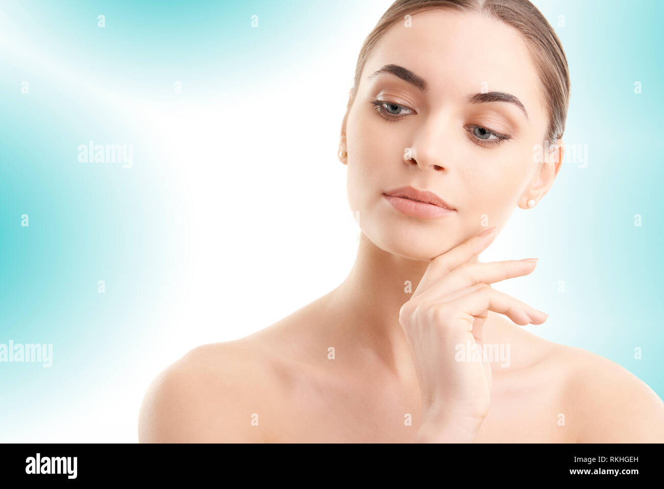 Portrait of beautiful young woman looking away and touching her face ...