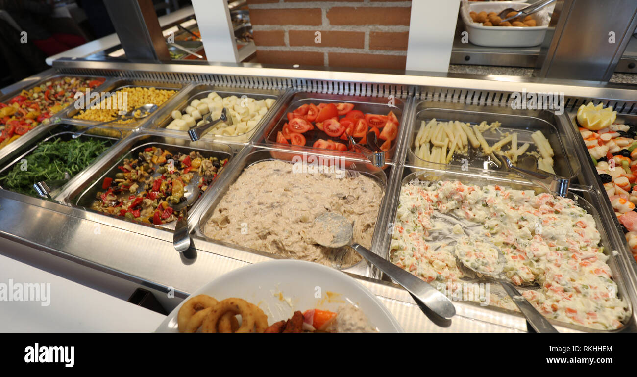 Inside a self service restaurant with many raw and cooked foods in many ...