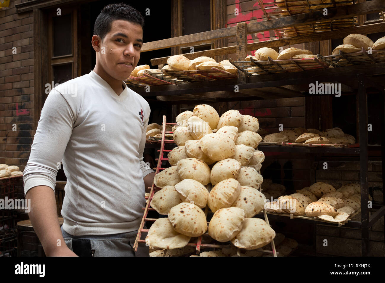 A young man takes out fresh bread (flatbread) at traditional Islamic ...