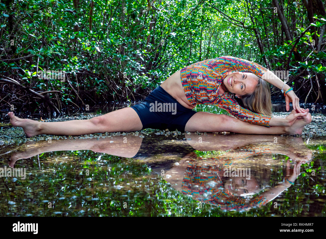 Young woman practicing yoga (Straddle Split) in a natural setting ...