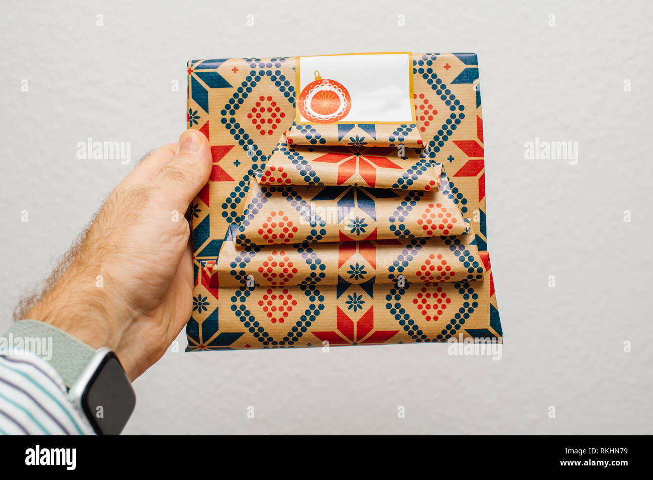 Man hand holding against white background gift wrapped in festive paper ...