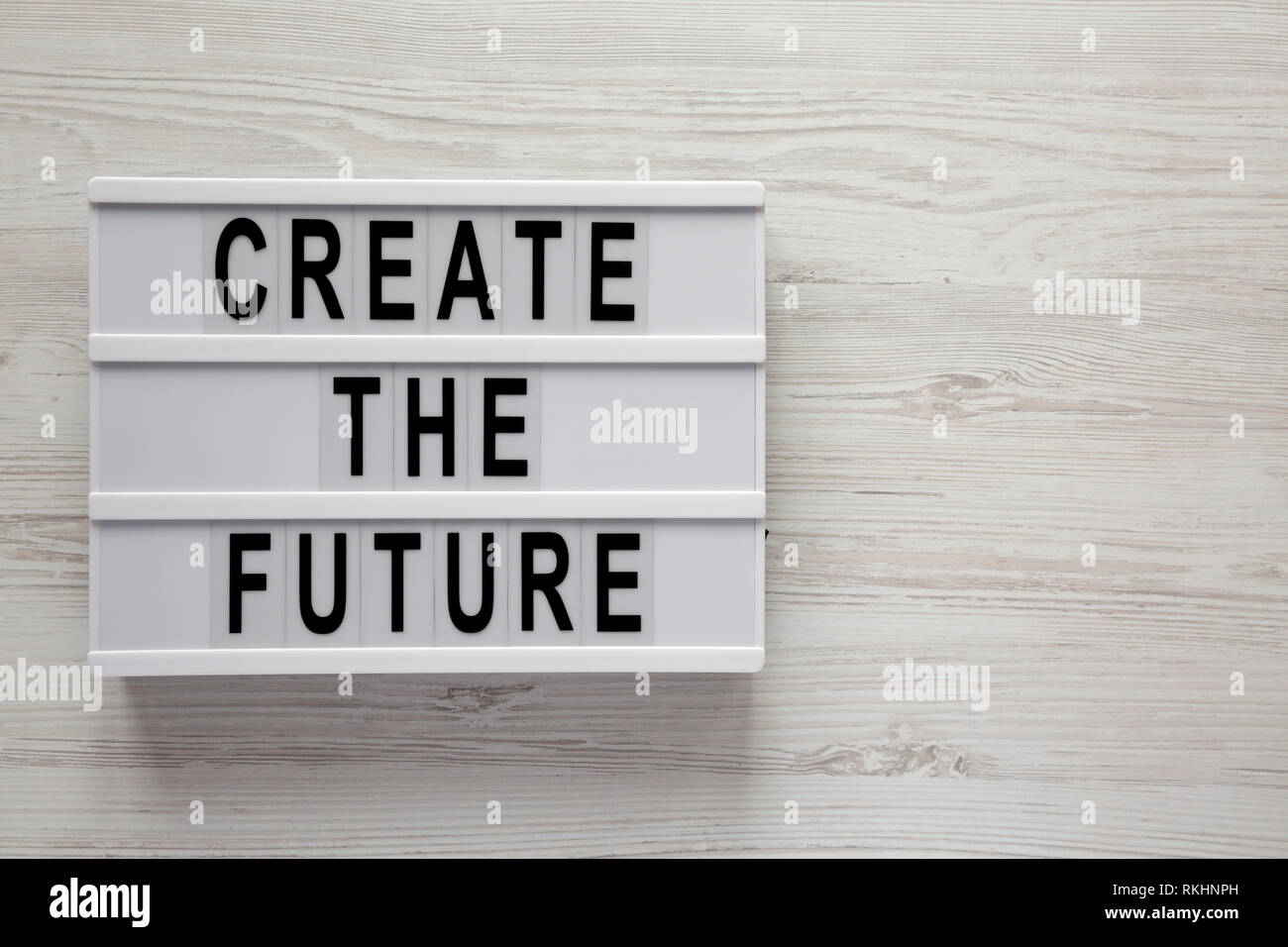 Modern board with text 'Create the future' on a white wooden table, top ...