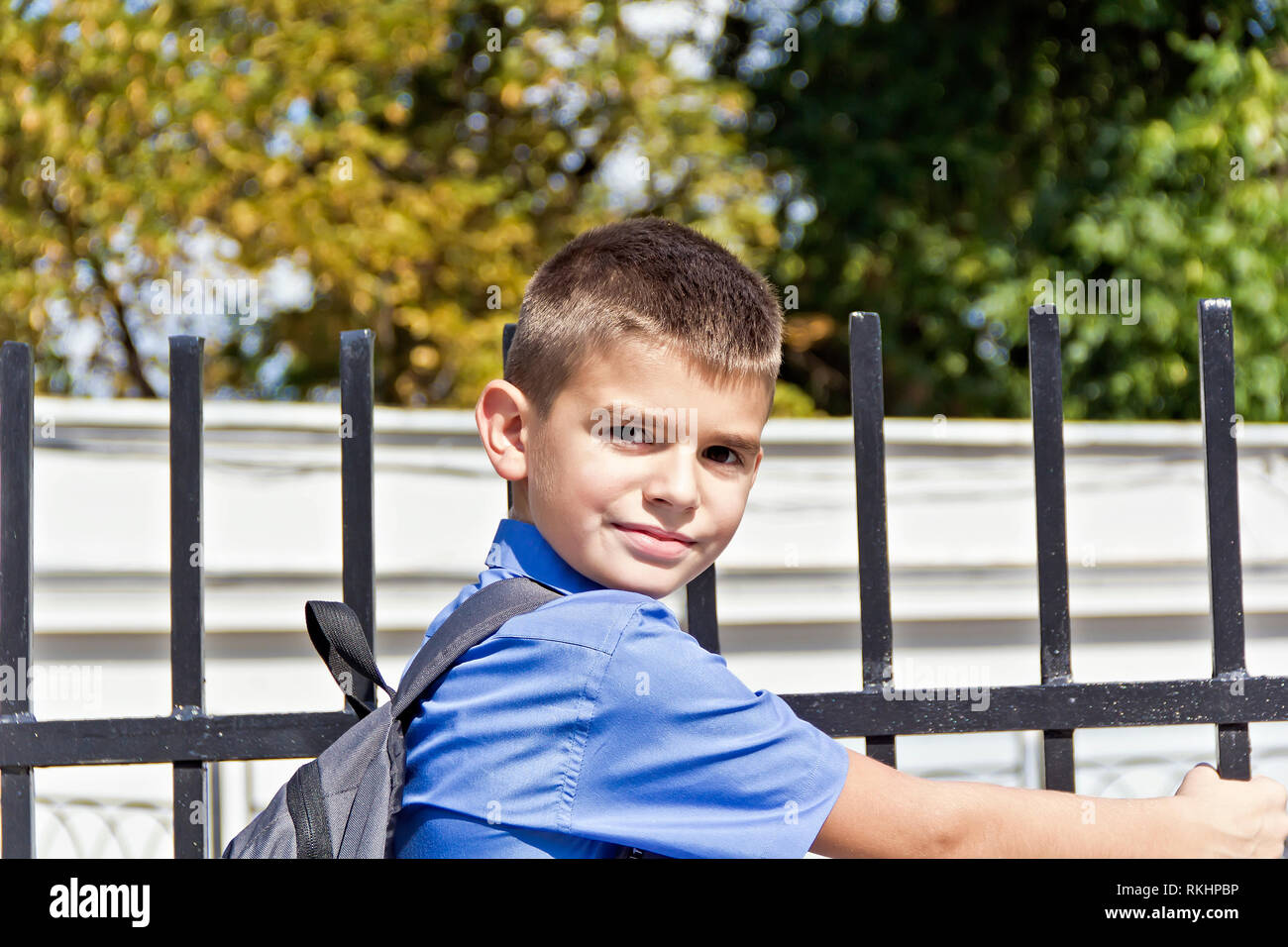 Boy are hanging on the fence with school backpack Stock Photo - Alamy