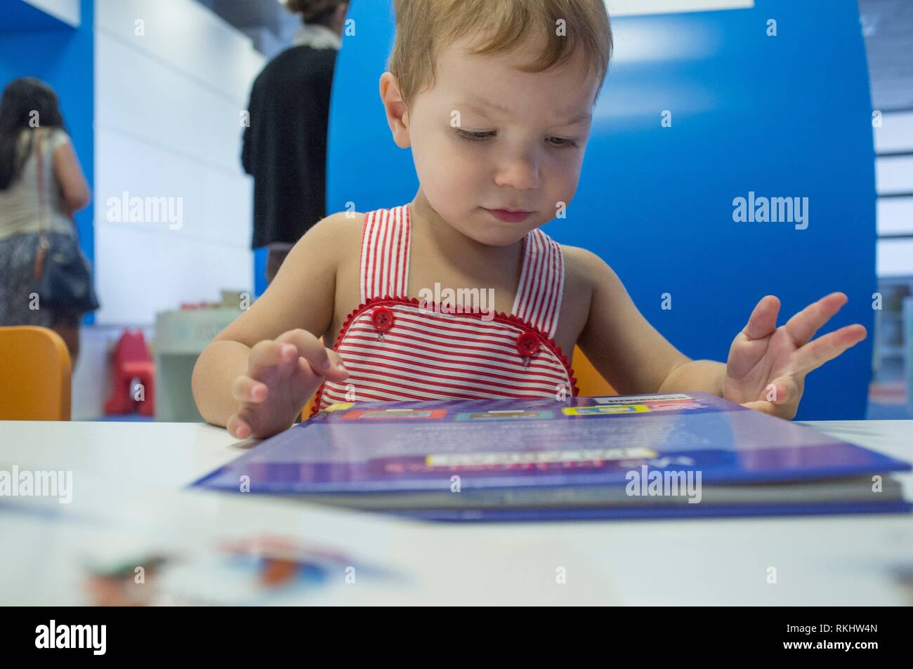 Adorable 2 years boy browsing stories at library. Discovering the books ...