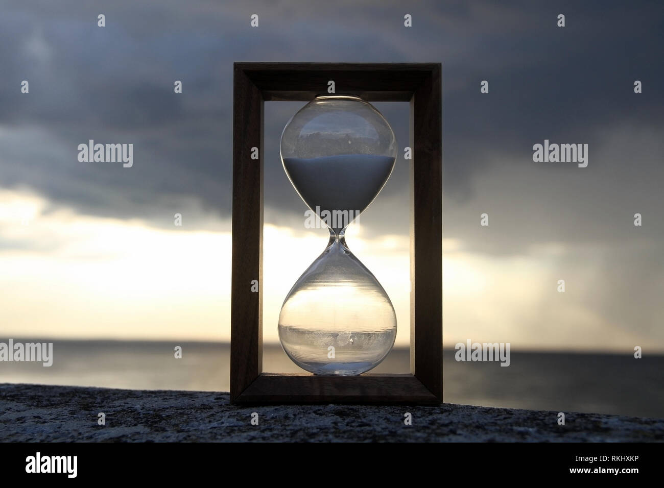 Glass sand time on concrete railing over cloudy sky Stock Photo - Alamy