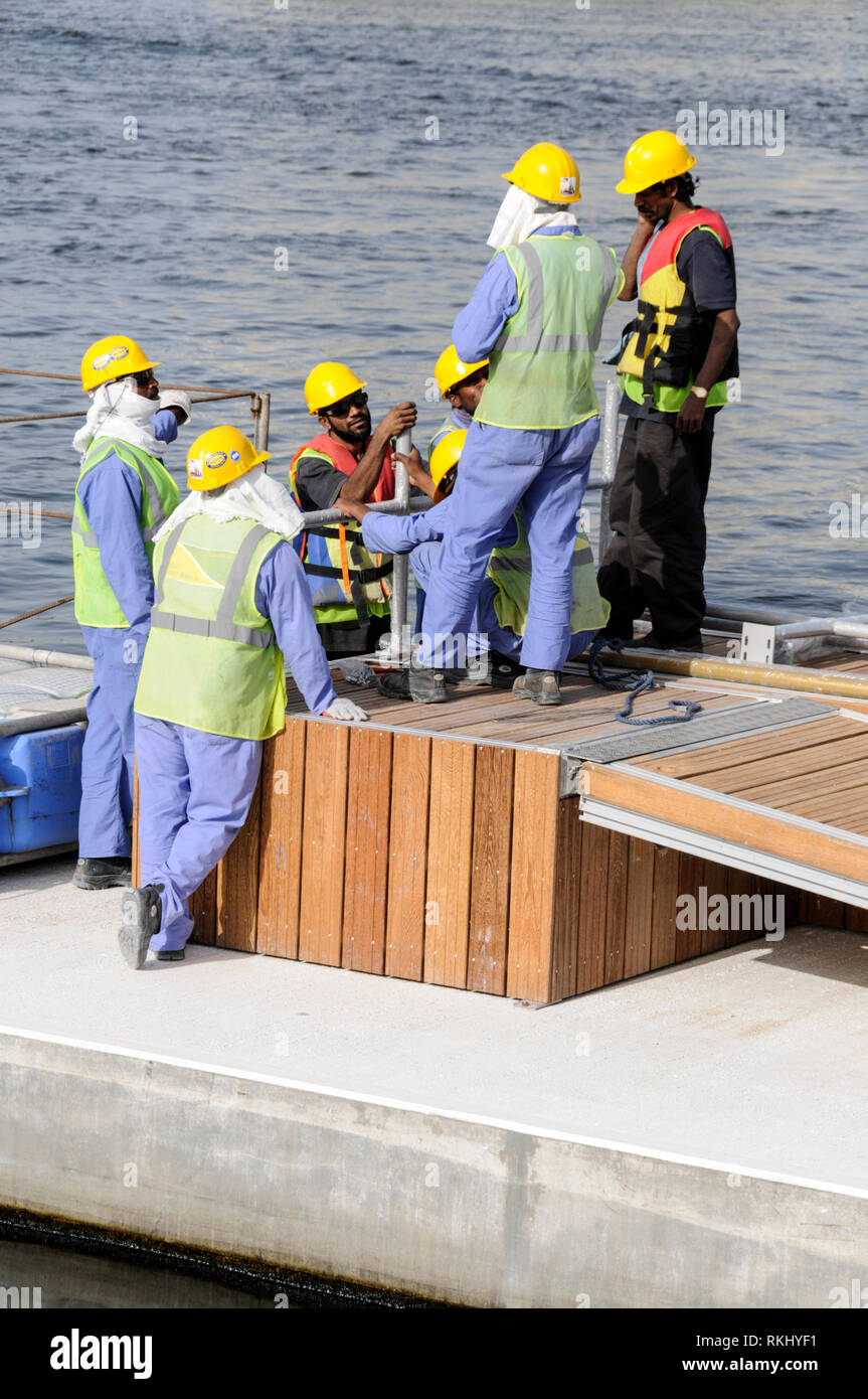 Asian construction workers on a floating platform on the Dubai Creek in ...