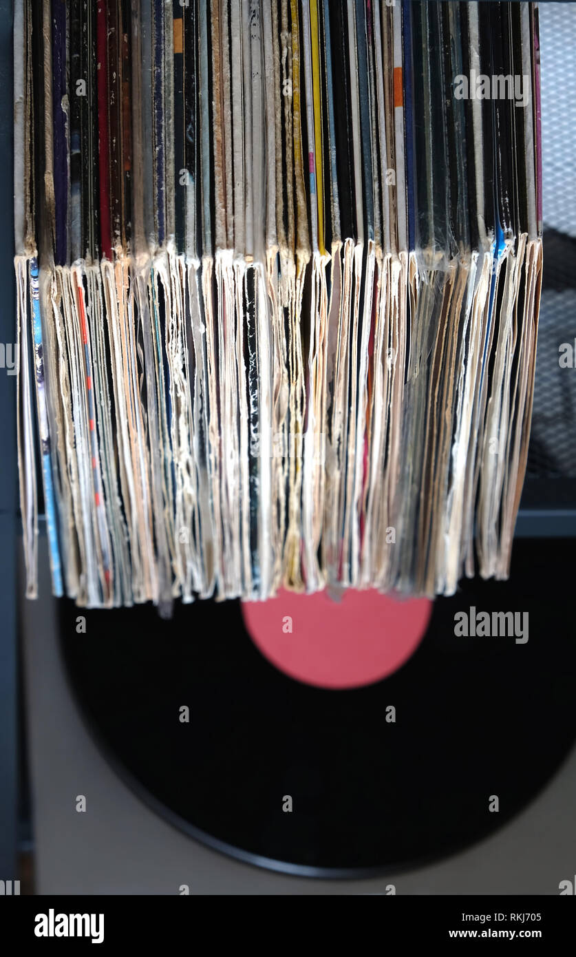Pile of many close standing vinyl records in old covers and turntable ...