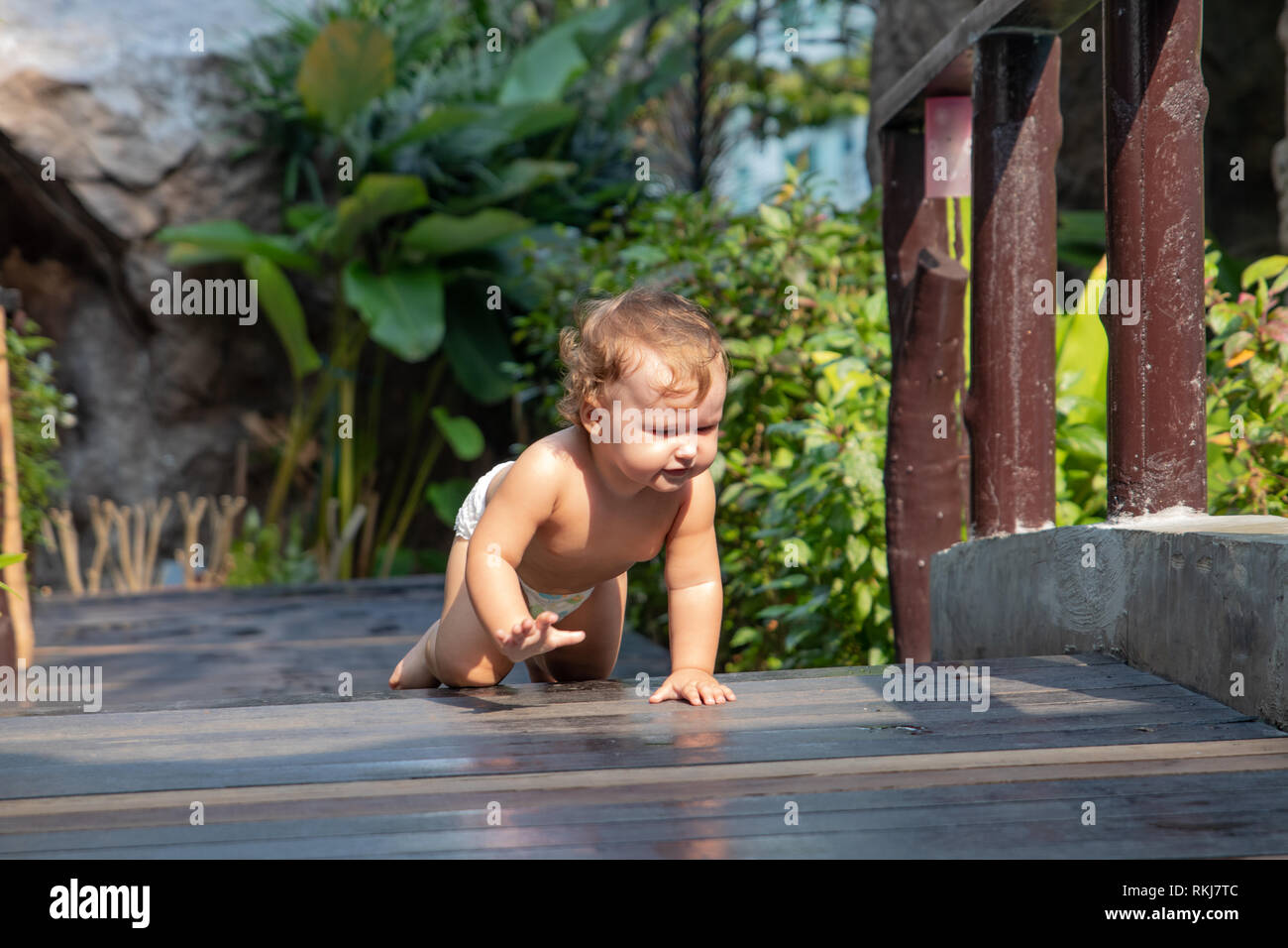Child crawls along the dark brown wooden walkway of the bridge at ...