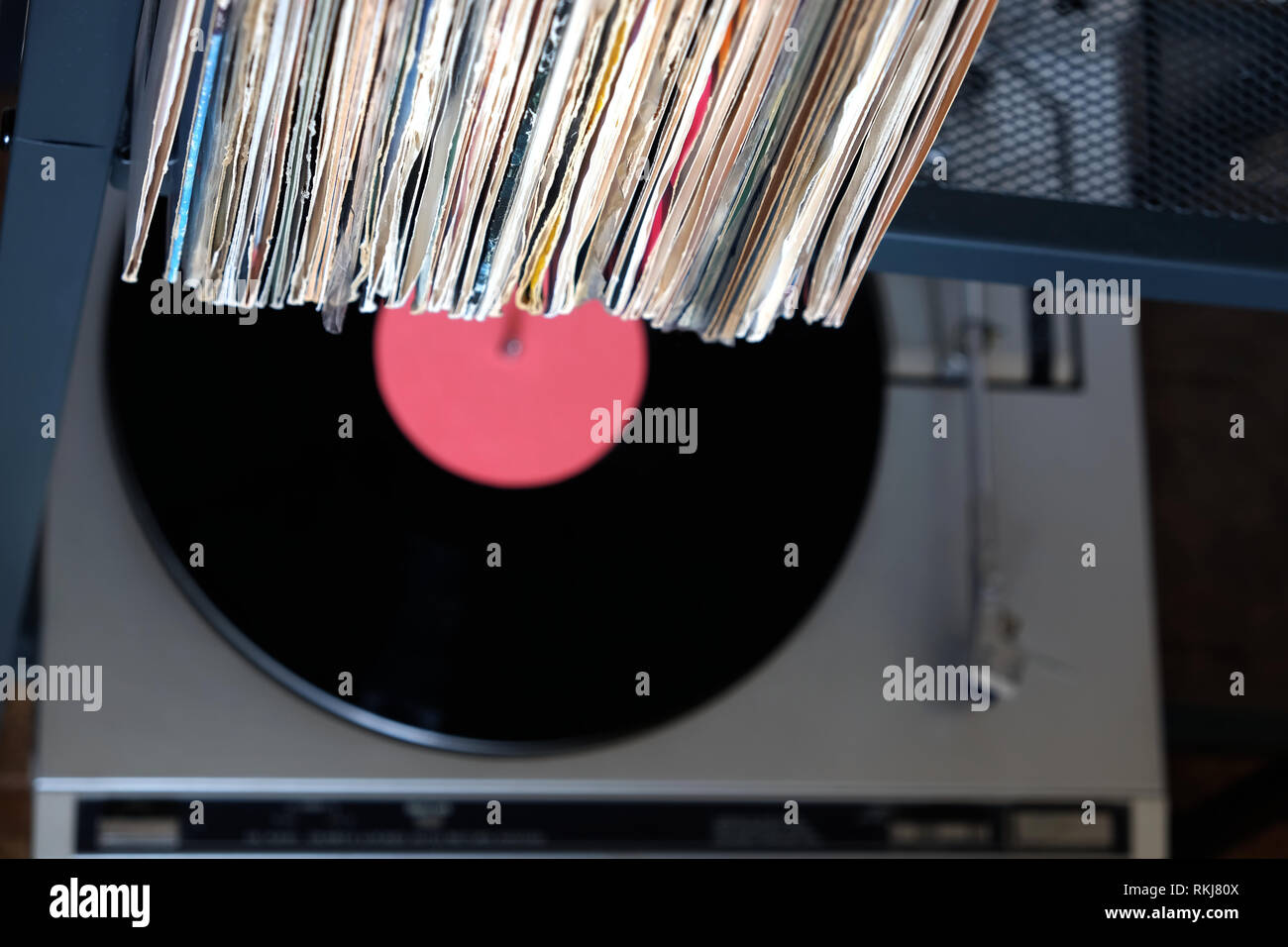 Pile of many close standing vinyl records in old covers and turntable ...