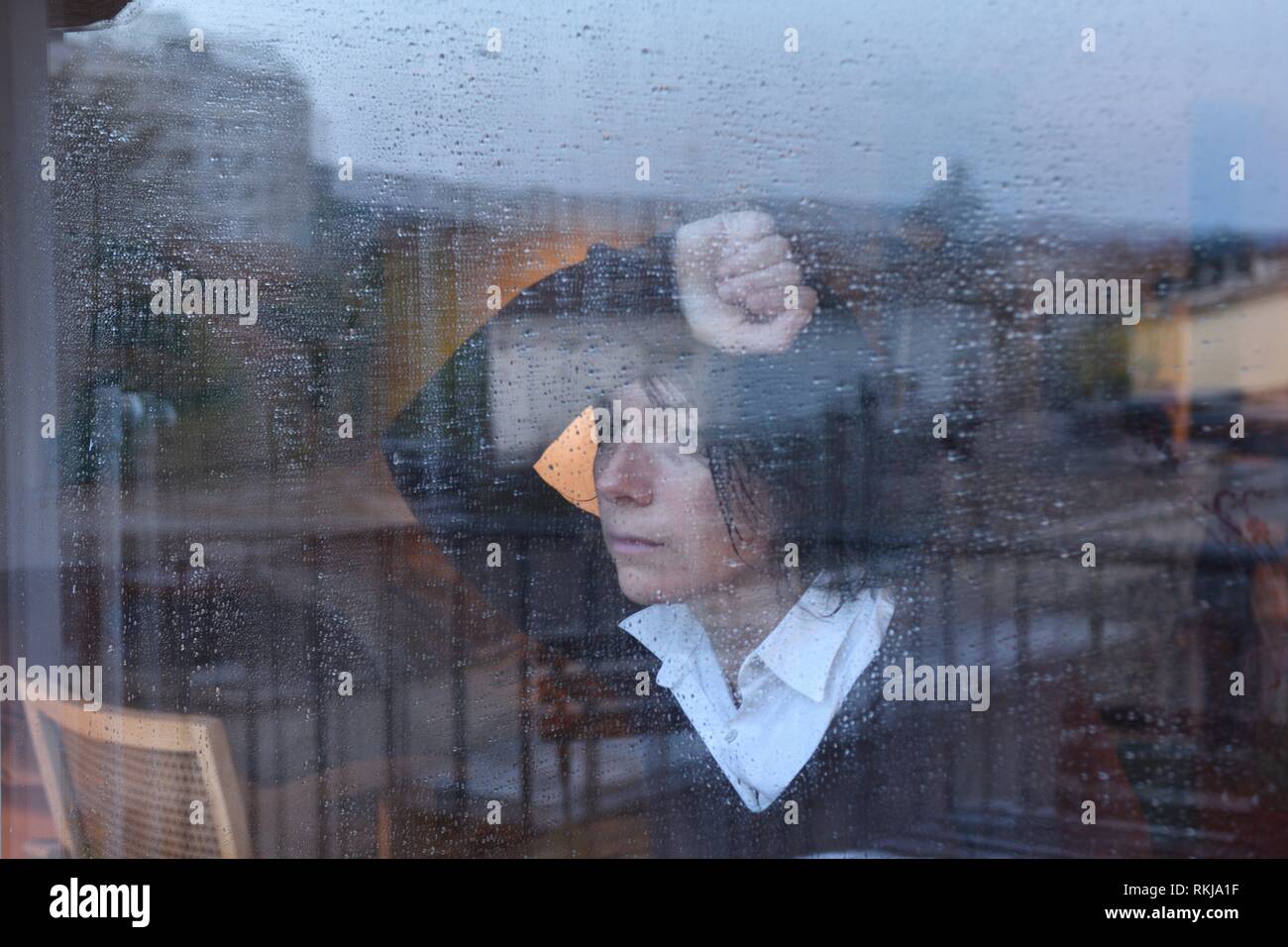 Woman looking out rainy window hi-res stock photography and images - Alamy