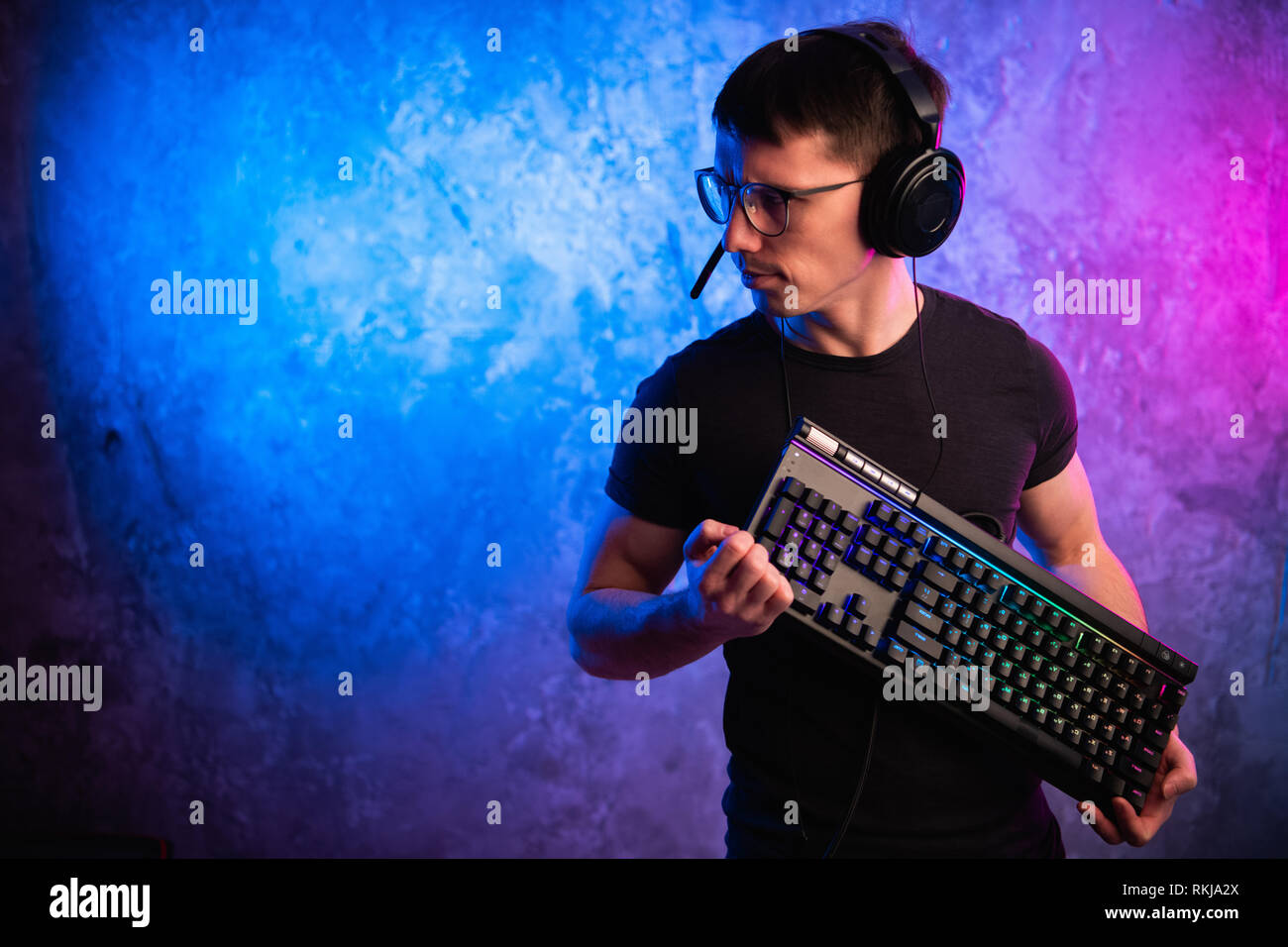 Professional Boy Gamer holding gaming keyboard over colorful pink and ...