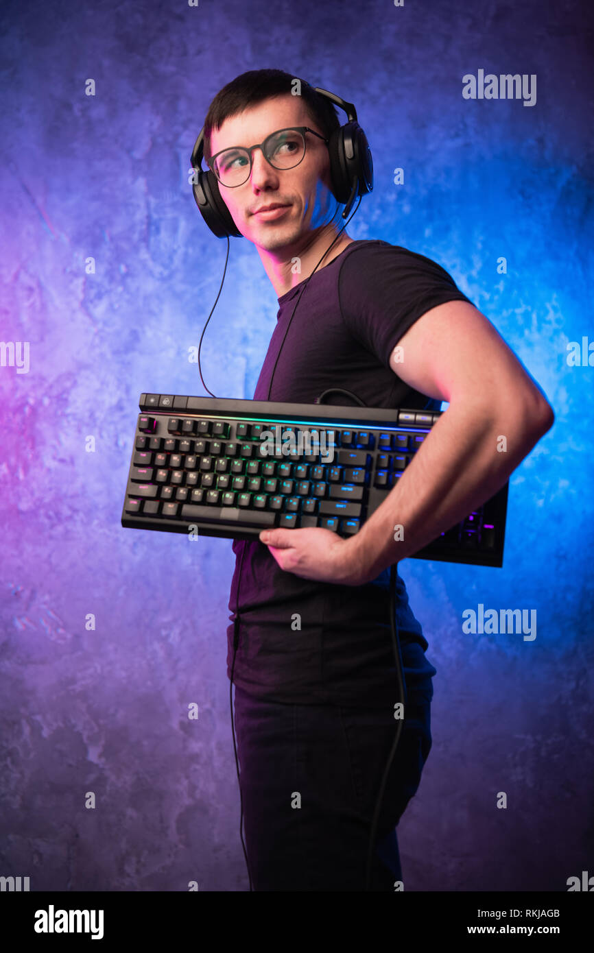 Gamer with keyboard over colorful pink and blue neon lit wall Stock ...