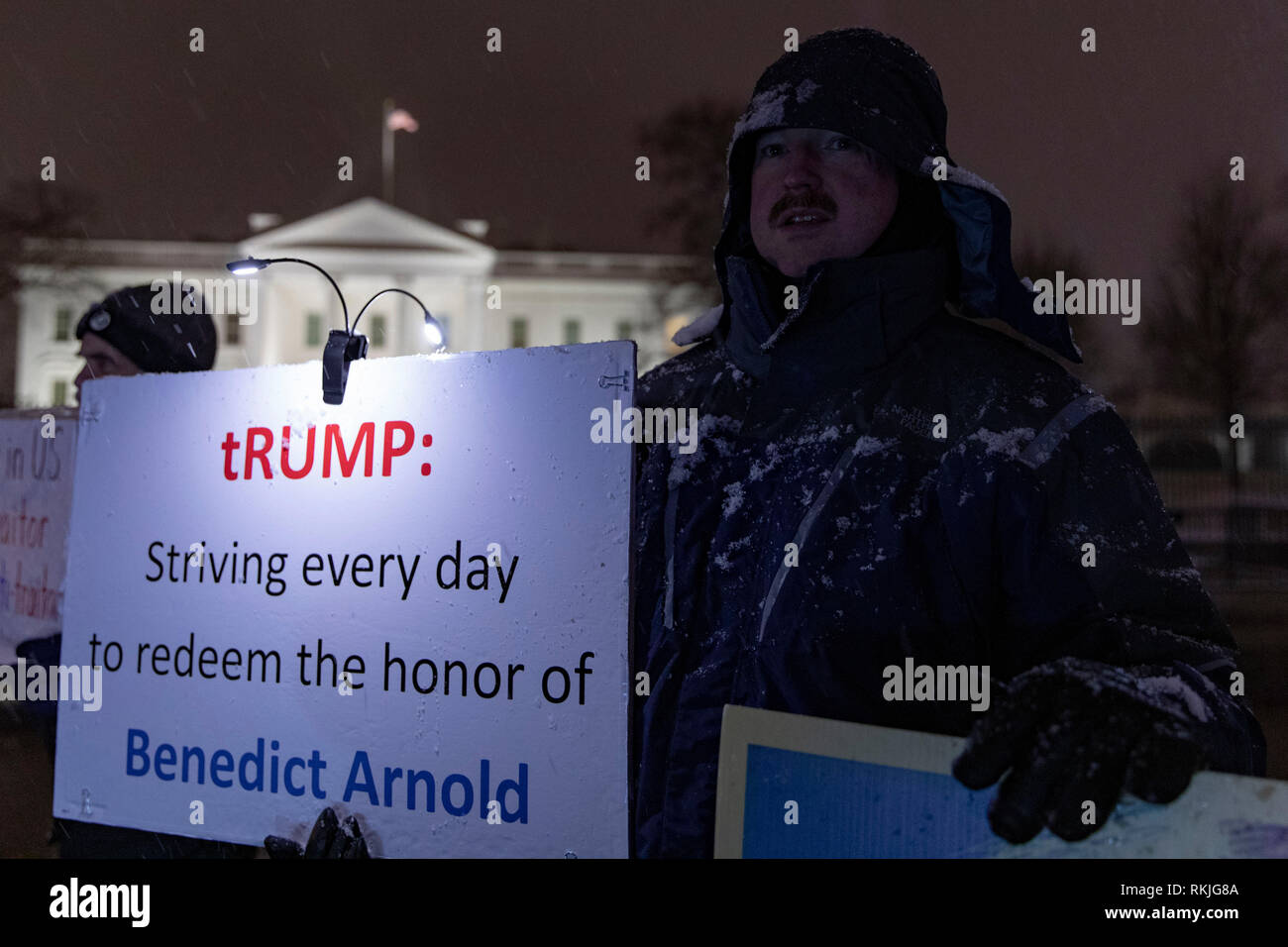 A demonstrator holds a protest sign while protesting outside of the ...