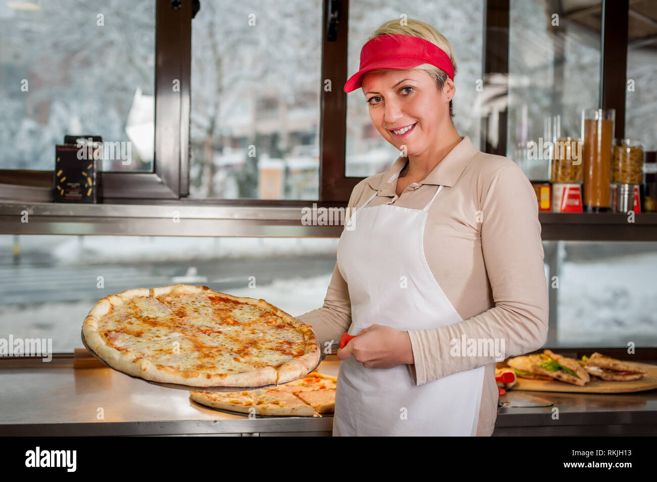 Female chef posing with delicious pizza in fast food restaurant. Tasty ...