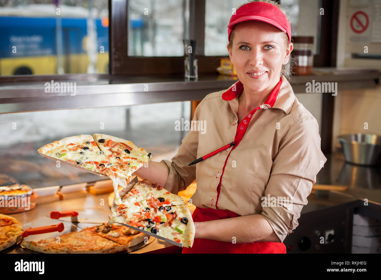 Female chef posing with slice of pizza in fast food restaurant. Tasty ...