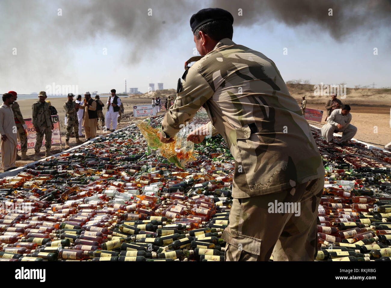 Karachi. 11th Feb, 2019. An official destroys bottles of liquor during ...