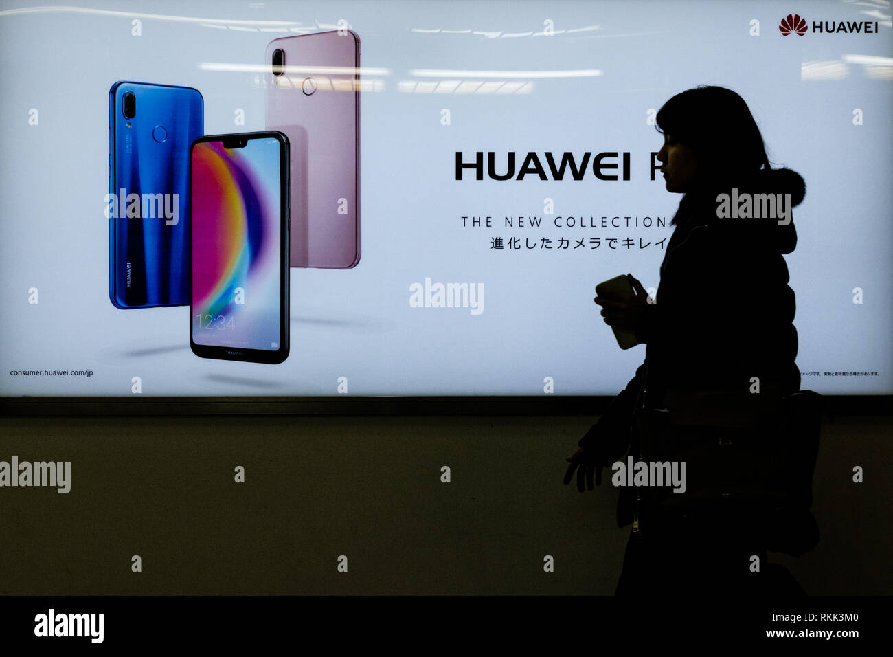 Tokyo, Japan. 12th Feb, 2019. A woman walks by a Chinese telecom giant ...