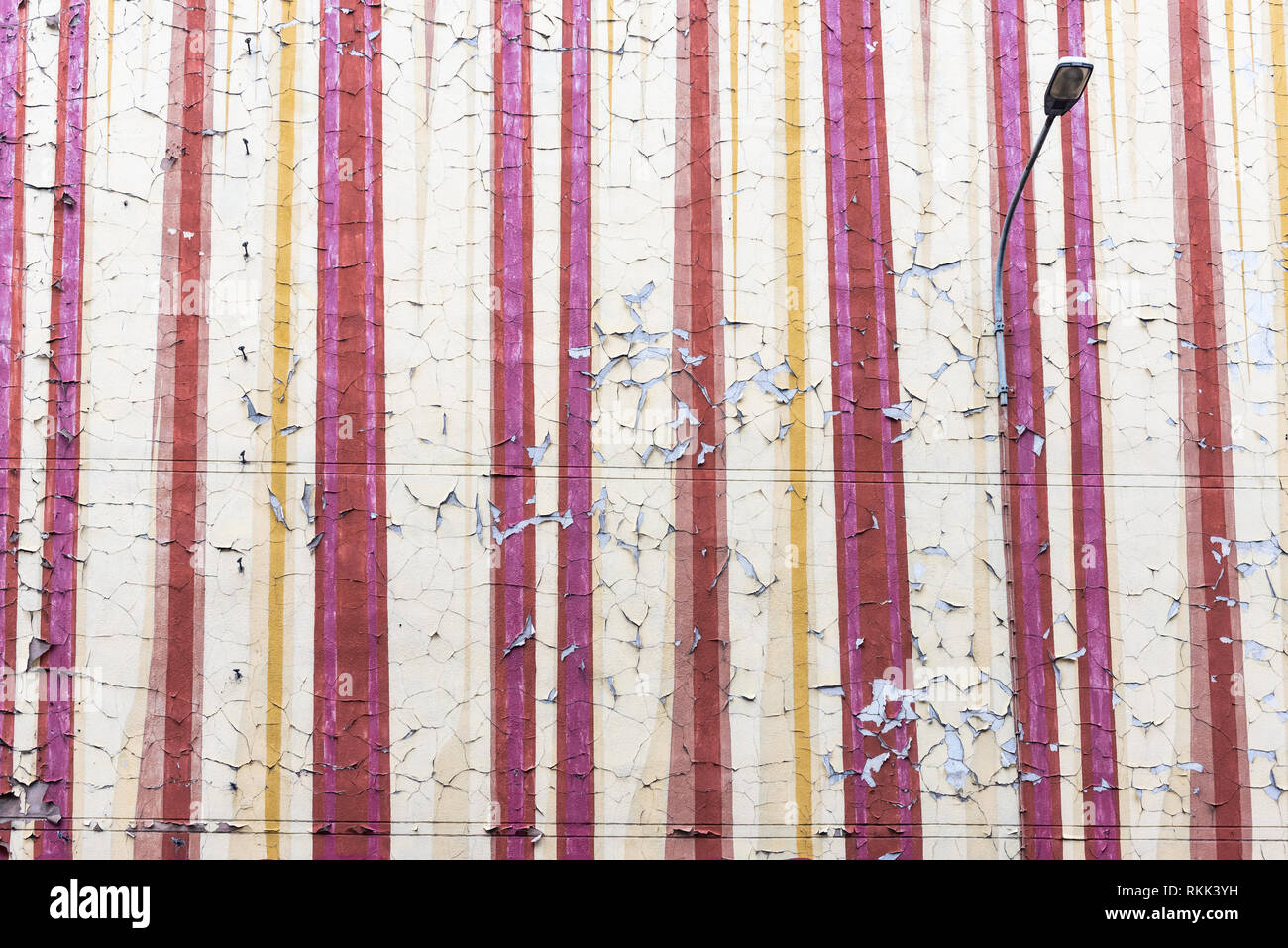 The crumbling flaking old paintwork on an old and aging wall of ...