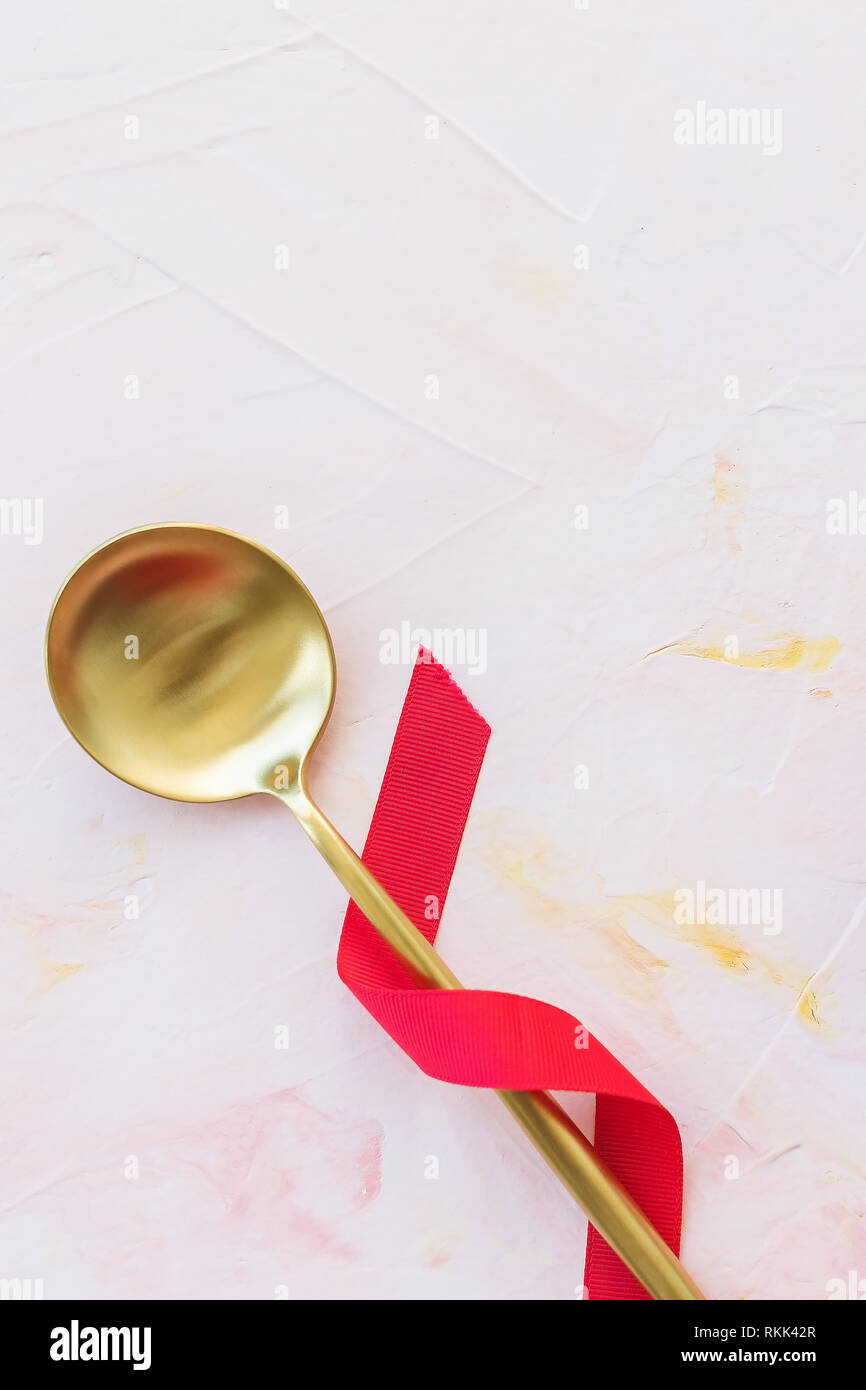 Golden spoon in red ribbon on a pink background . Spring holidays ...