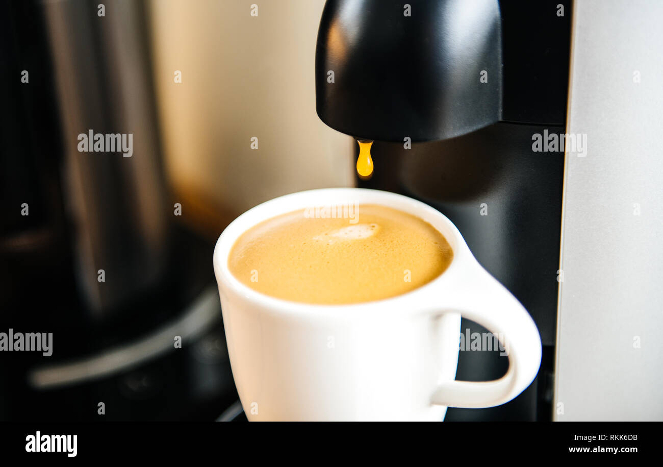 Delicious coffee pouring from the caffe espresso machine in the white ...