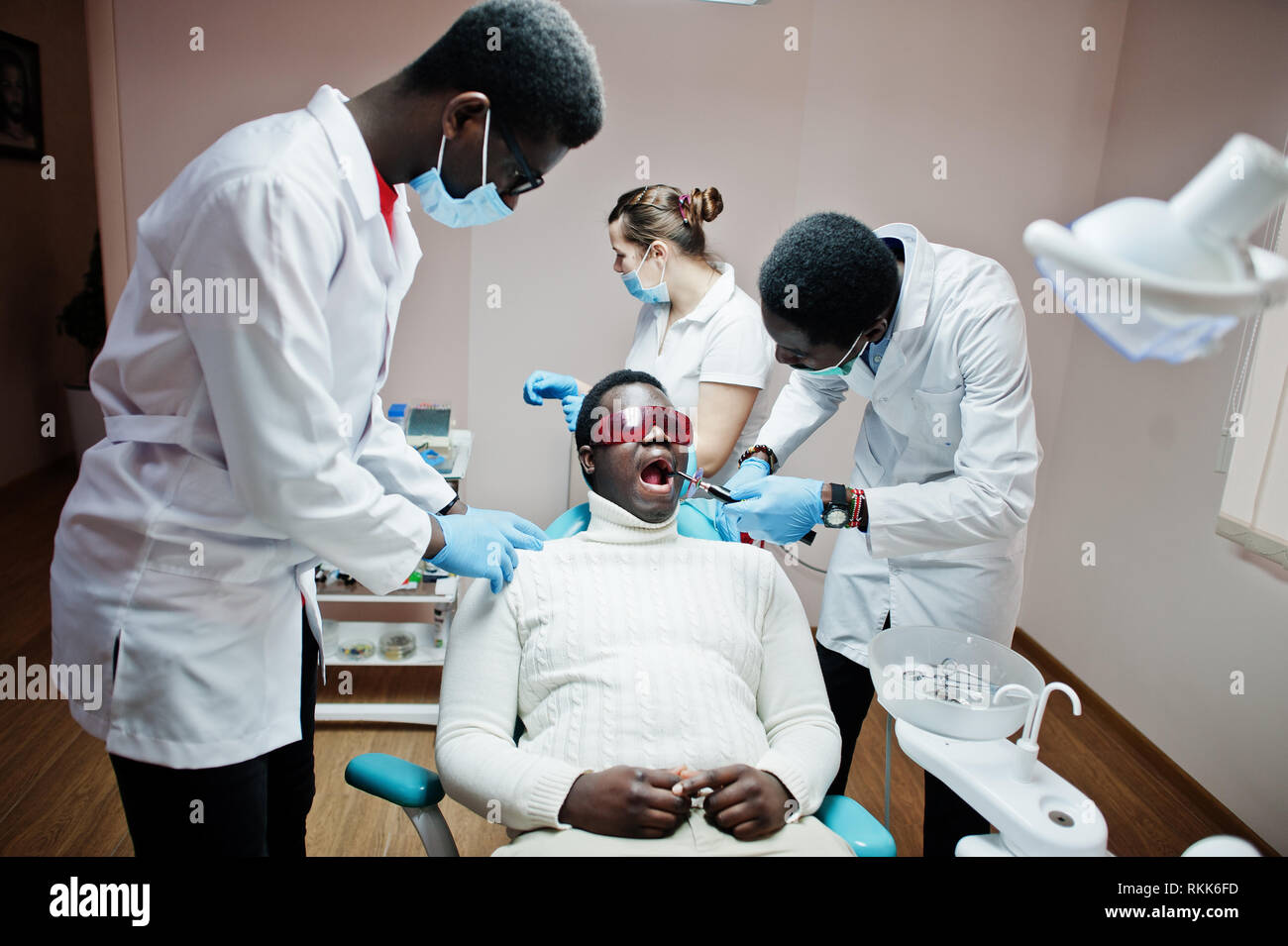 Multiracial dentist doctors team. African american man patient at UV ...
