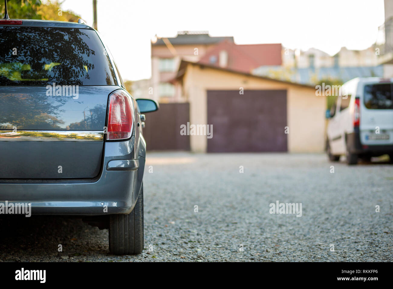 New shiny gray car parked on gravel suburbs road on blurred sunny ...