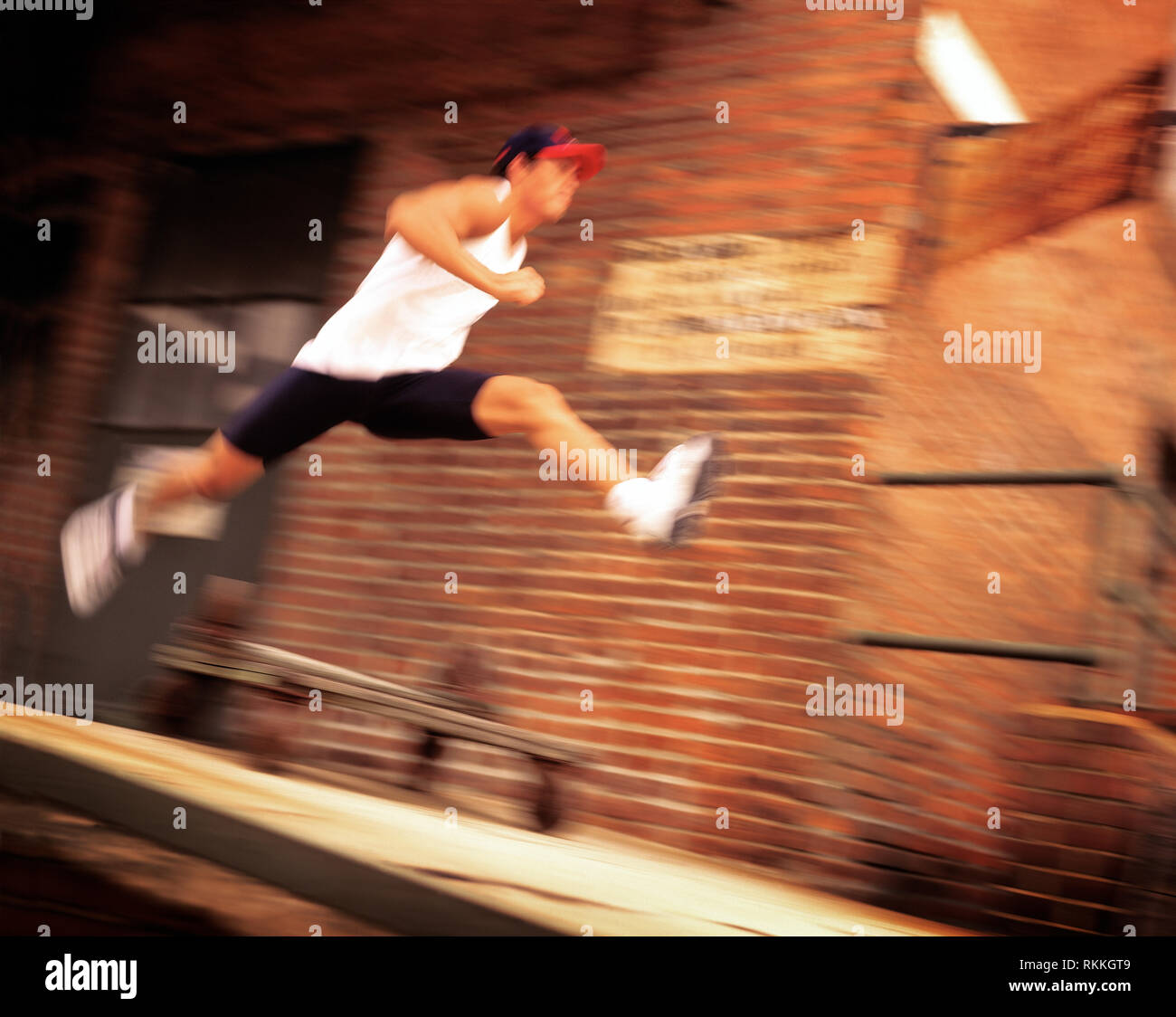 Side view of a young man performing a long jump Stock Photo - Alamy