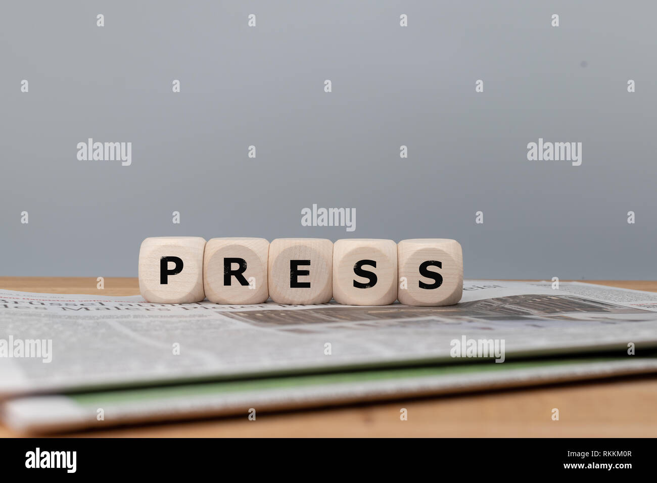 Dice form the word "PRESS" on a newspaper in front of a grey background ...