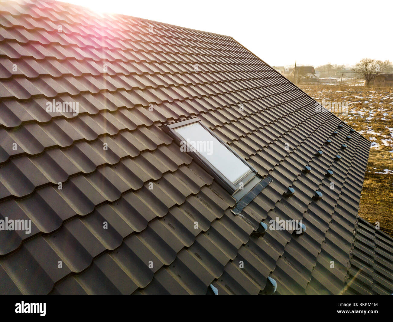 Close-up of new attic plastic window installed in shingled house roof ...