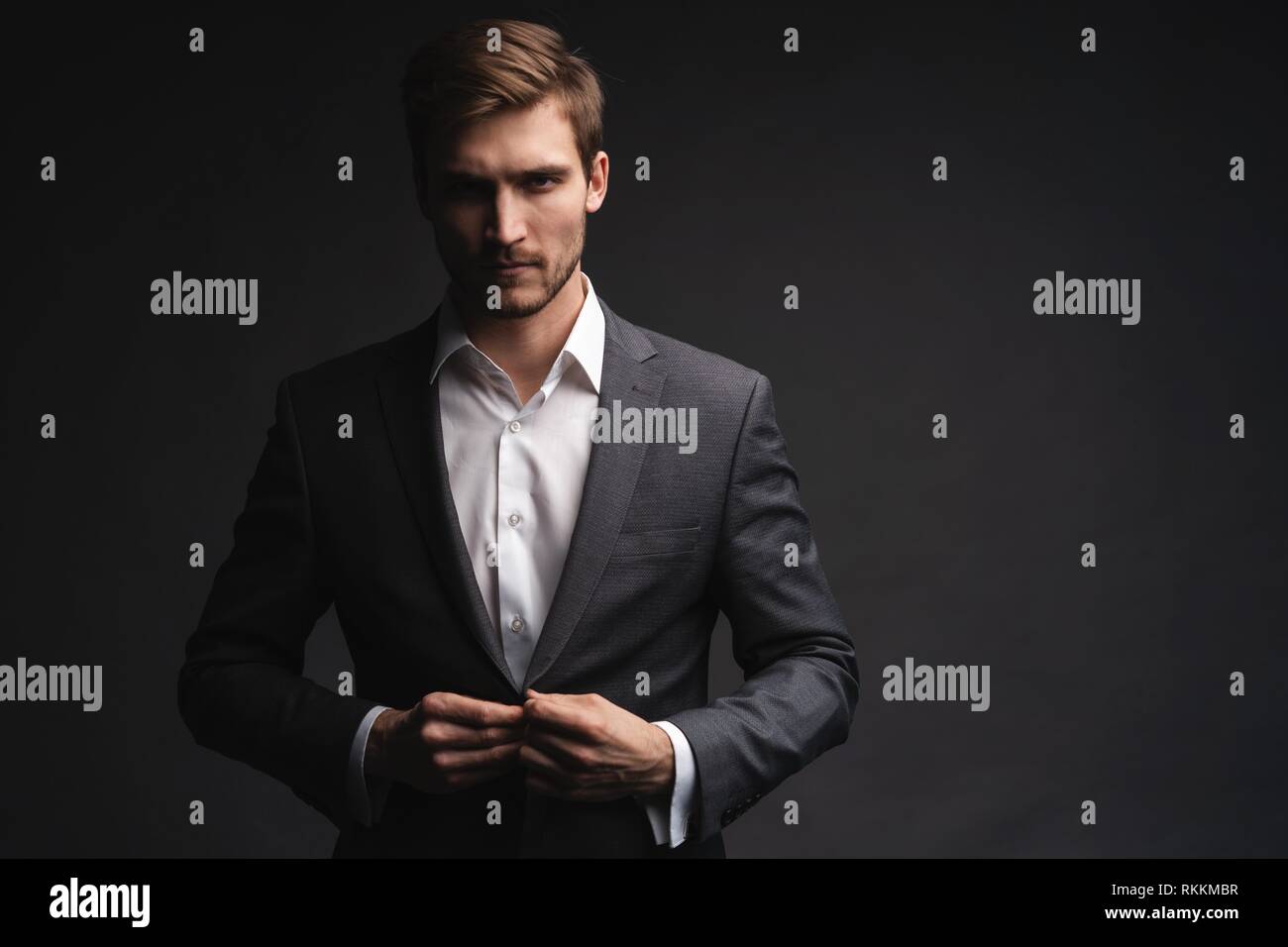 Portrait of serious handsome man in gray suit buttoning jacket Stock ...