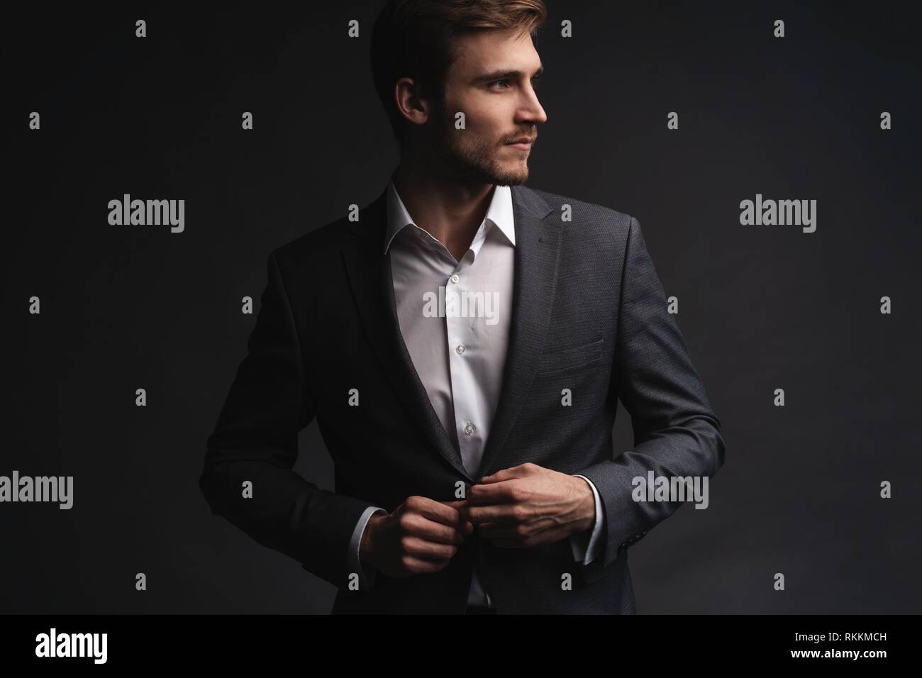 Portrait of serious handsome man in gray suit buttoning jacket Stock ...