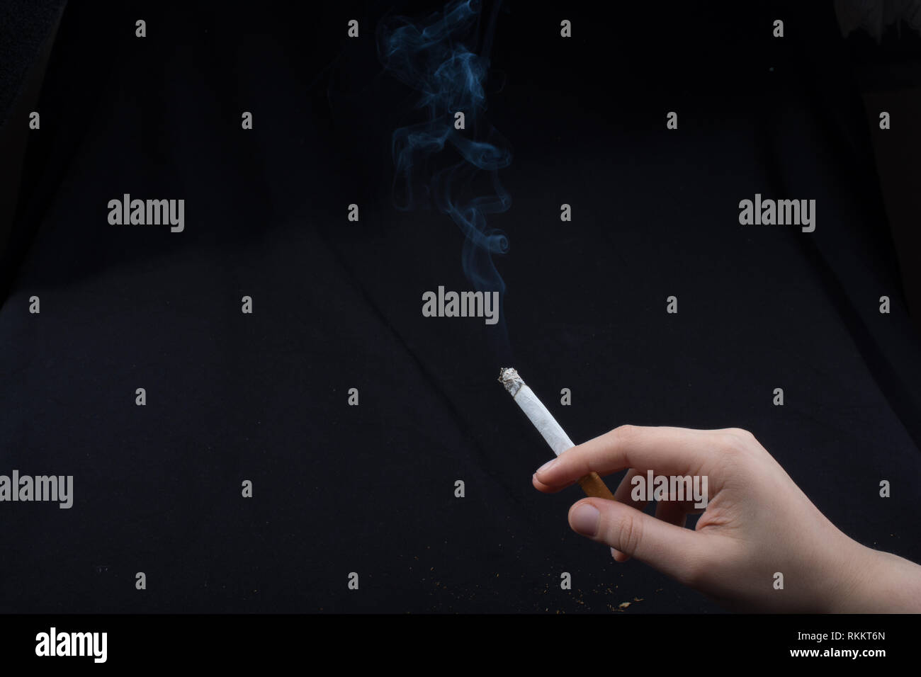 Hand is holding smoking cigarette with smoke around Stock Photo - Alamy