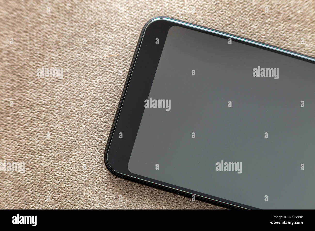New black modern cellphone isolated on light cloth copy space ...