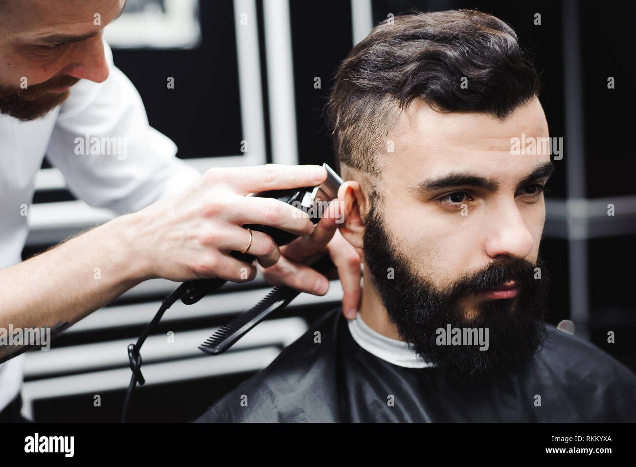 Master cuts hair and beard of men in the barbershop, hairdresser Stock ...