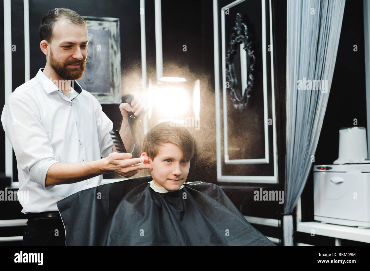 Young handsome barber making haircut of cute boy in a barbershop Stock ...